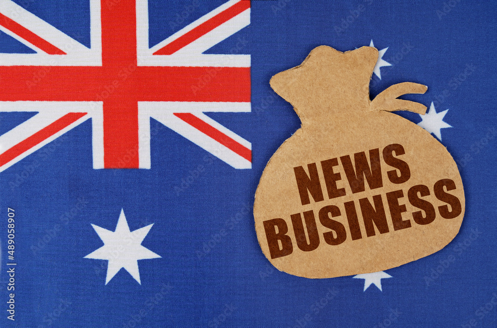 On the flag of Australia lies a cardboard figure of a money bag with ...