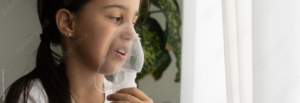Kid girl makes inhalation with a nebulizer. sick child holding ...