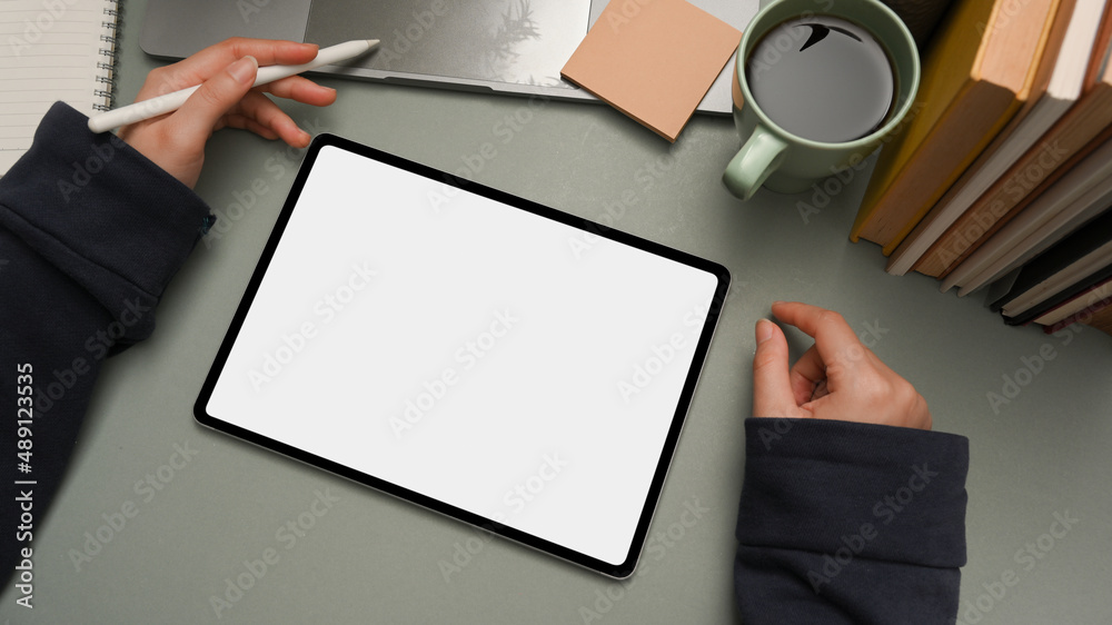 Workspace with female hands holding stylus pen and working on tablet ...