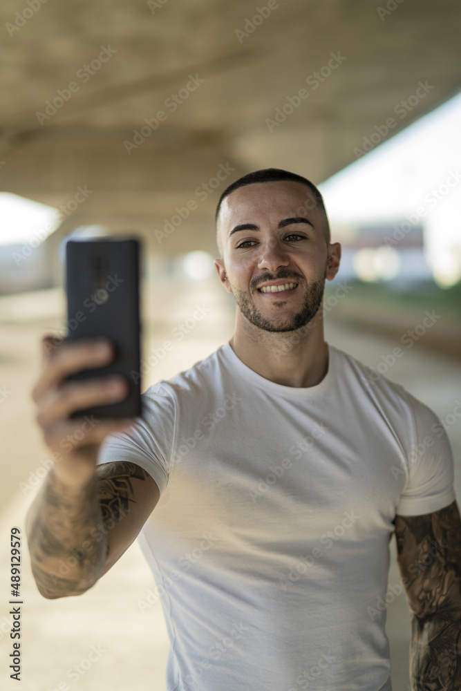 A cheerful muscular European guy with cool tattoos doing a selfie or a ...