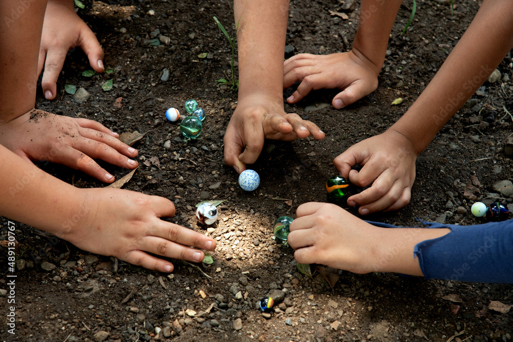 Children playing with marbles in the schoolyard at recess time ...
