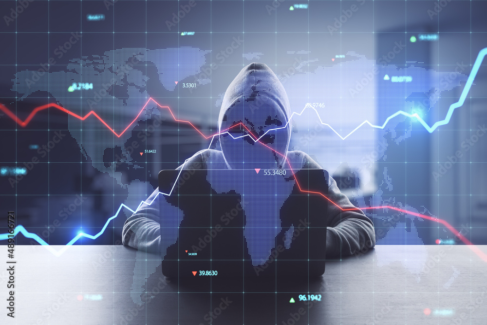 Hacker at desktop using computers with creative glowing blue map hologram with chart and grid on ...