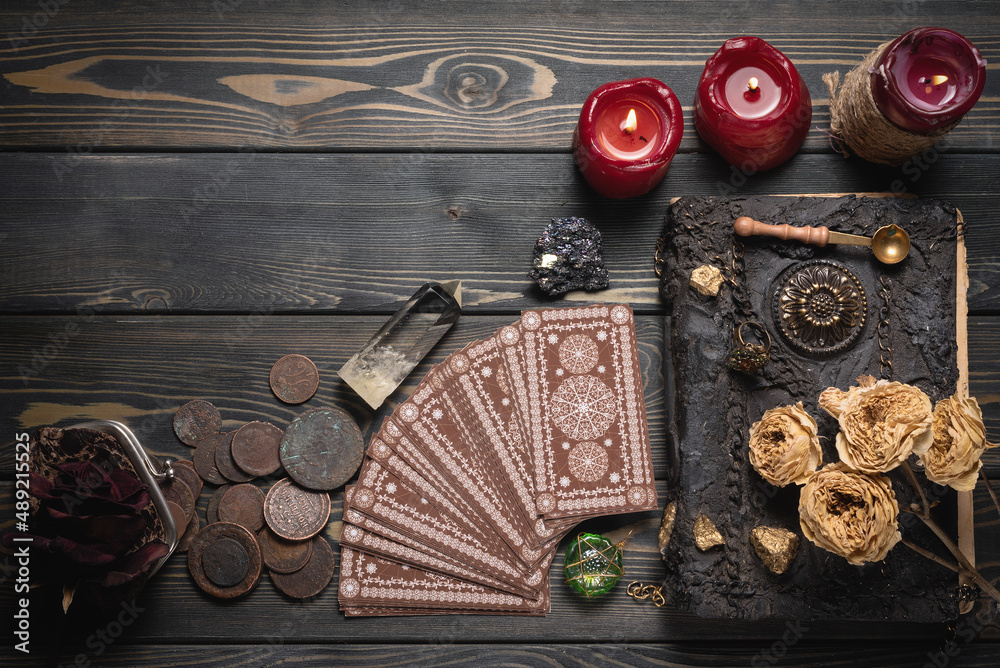 Tarot cards and magic book on the old wooden fortune teller table ...