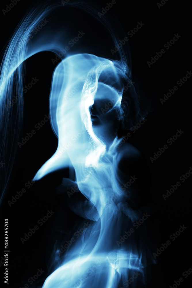 Abstract woman silhouette in light trails of light painting with blue ...