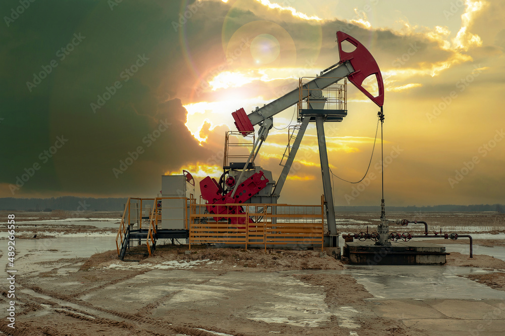 Fotka „Crude oil pump jack at oilfield on sunset backround. Fossil ...