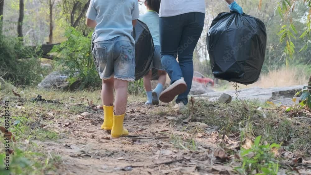 Group of Asian volunteer families tying a garbage bag and carry it out ...