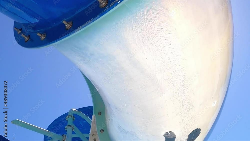 Underneath a transparent water slide, a silhouette of two people ...