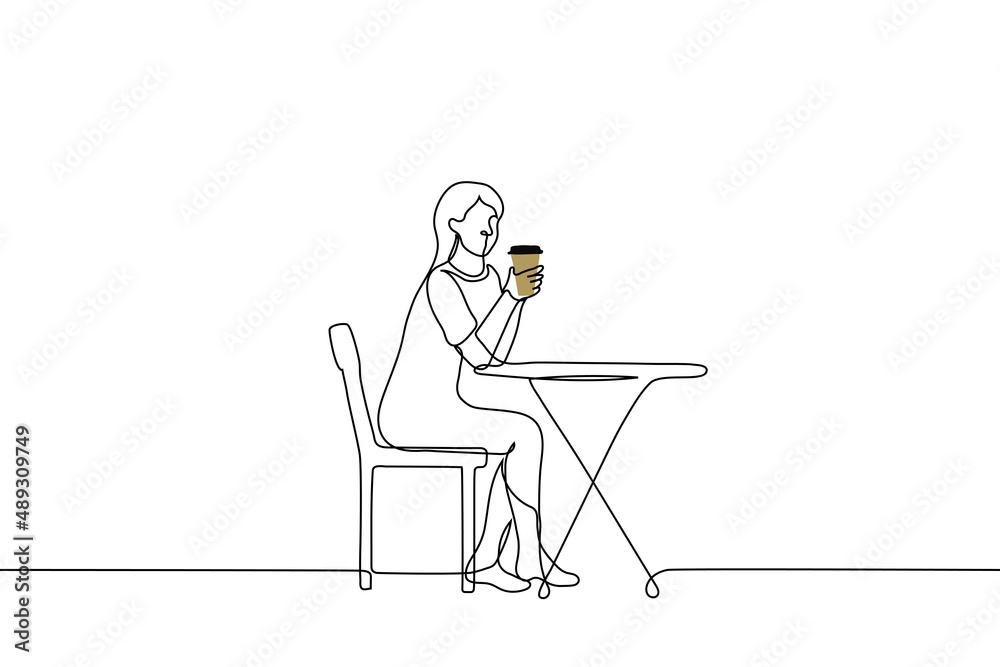 young woman sitting at a round table and drinking from a large cup of ...