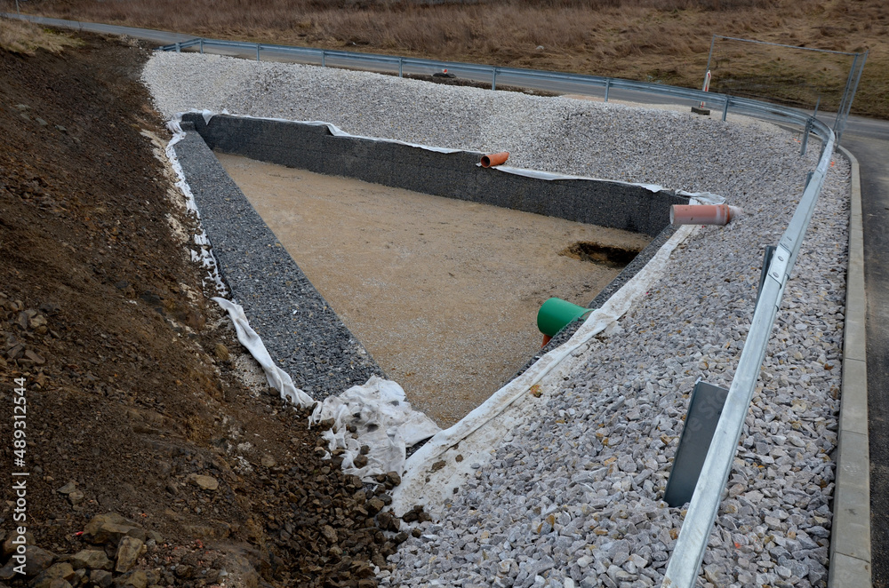 triangle-shaped drainage pond with stone wall paneling and gabion walls ...