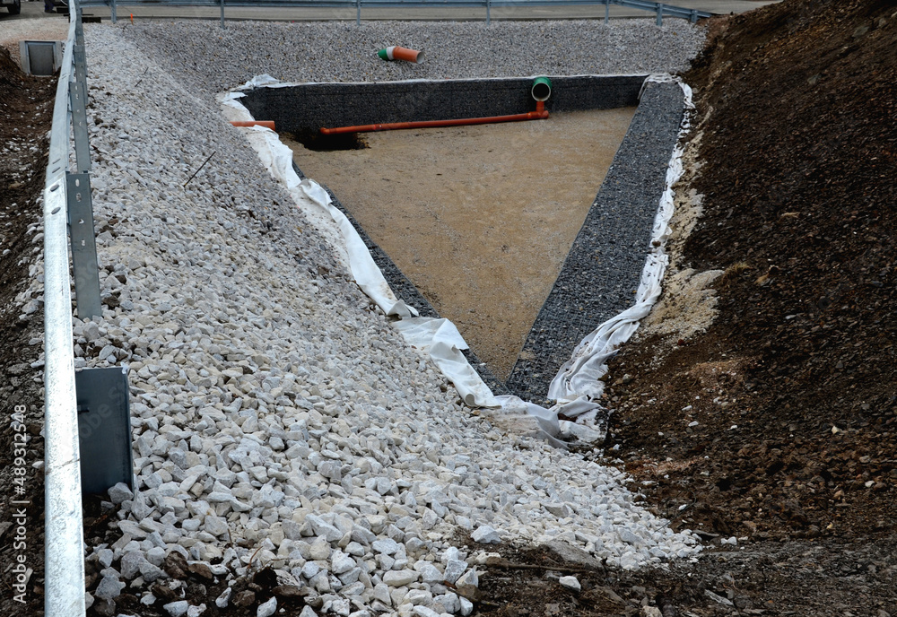 triangle-shaped drainage pond with stone wall paneling and gabion walls ...