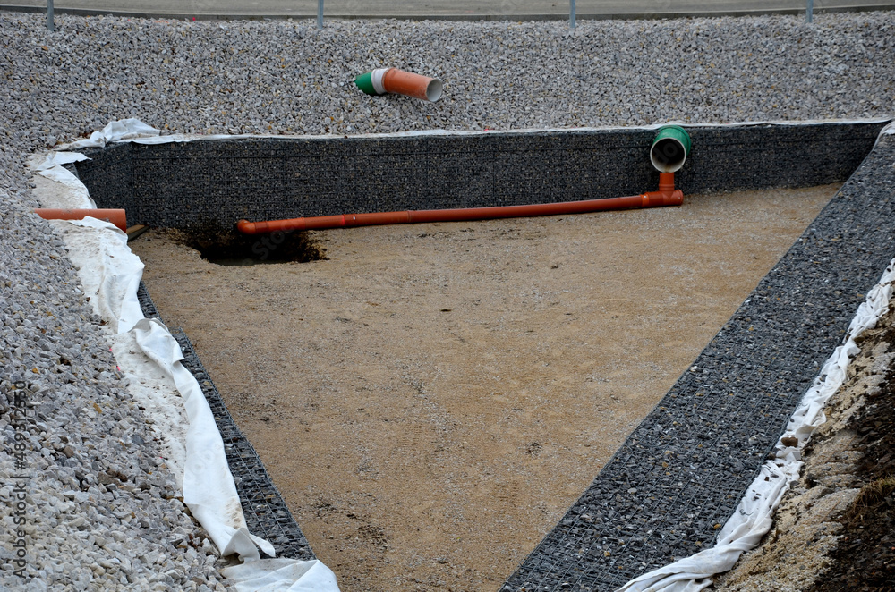 triangle-shaped drainage pond with stone wall paneling and gabion walls ...