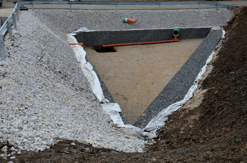 triangle-shaped drainage pond with stone wall paneling and gabion walls ...