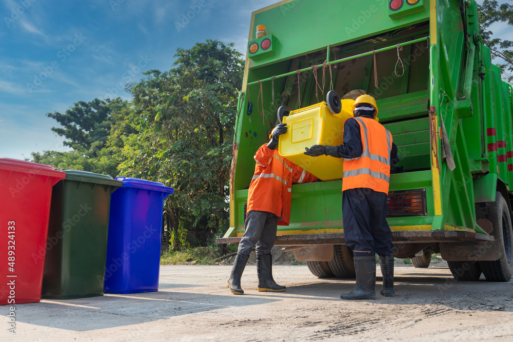 Teamwork garbage men working together on emptying dustbins for trash ...