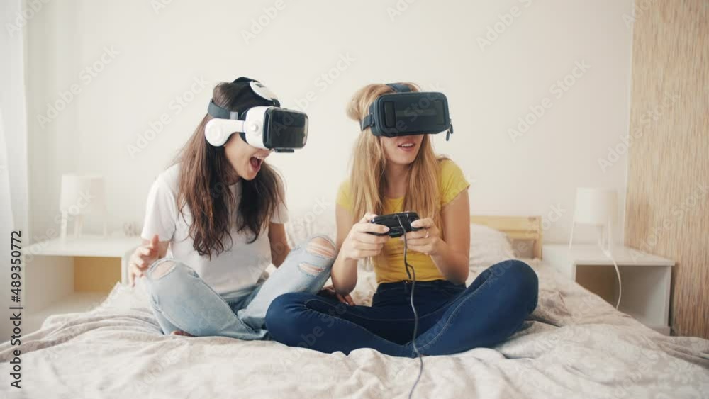 Exited girls in VR helmets at home. Two women in virtual reality ...