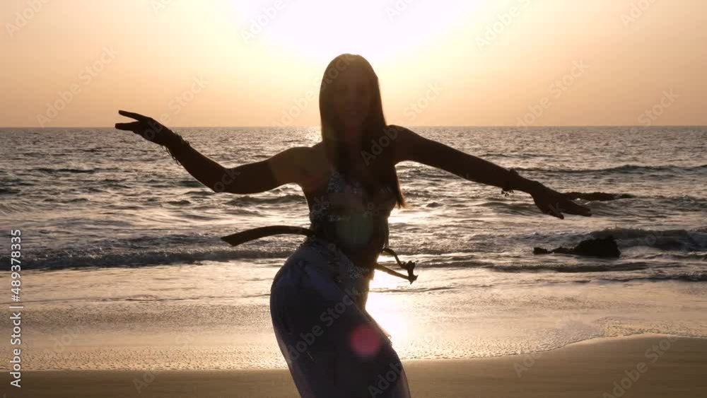 dancer woman shaking her hips dancing belly dance on the shore of the ...