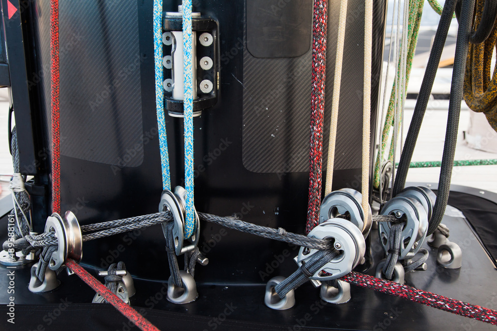 Part of the mast and hull of a sailing yacht, with multi-colored ropes ...