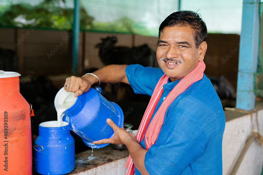 Happy smiling milk dairy farmer busy working while looking at camera ...
