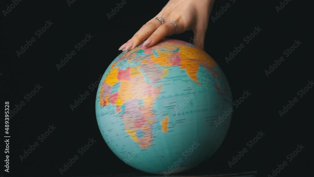 Geographical globe is twisted around its axis by a female hand ...