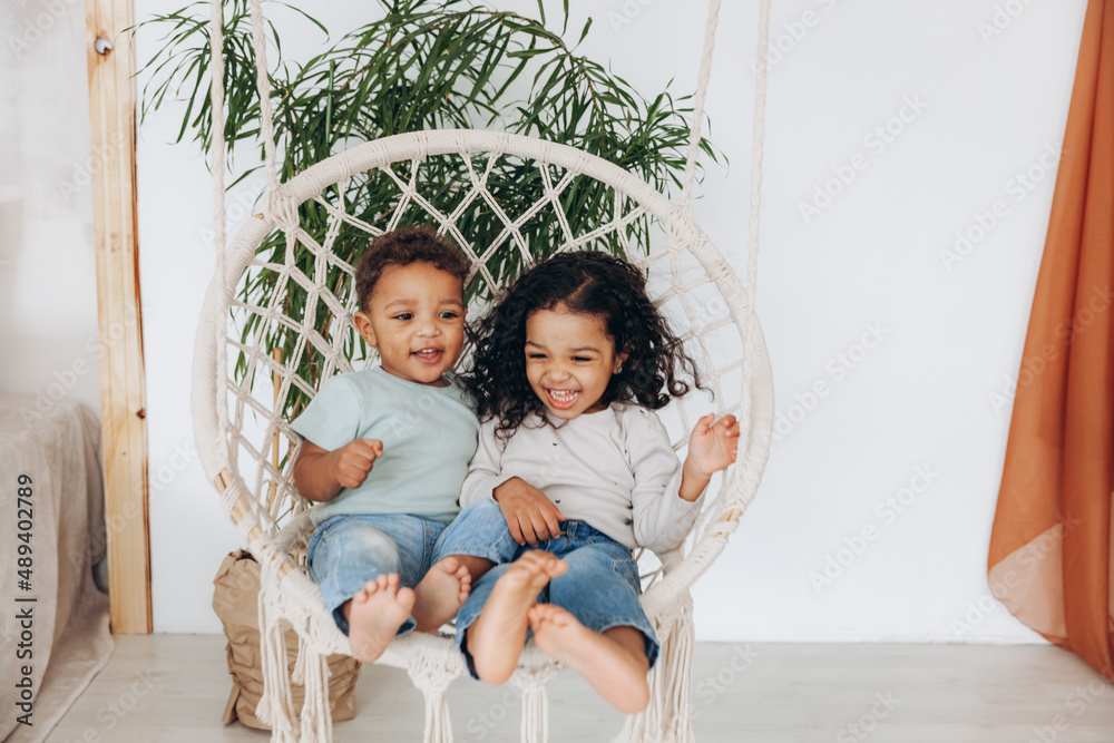 dark-skinned mulattoes A boy and a girl sit in a wicker hanging chair ...