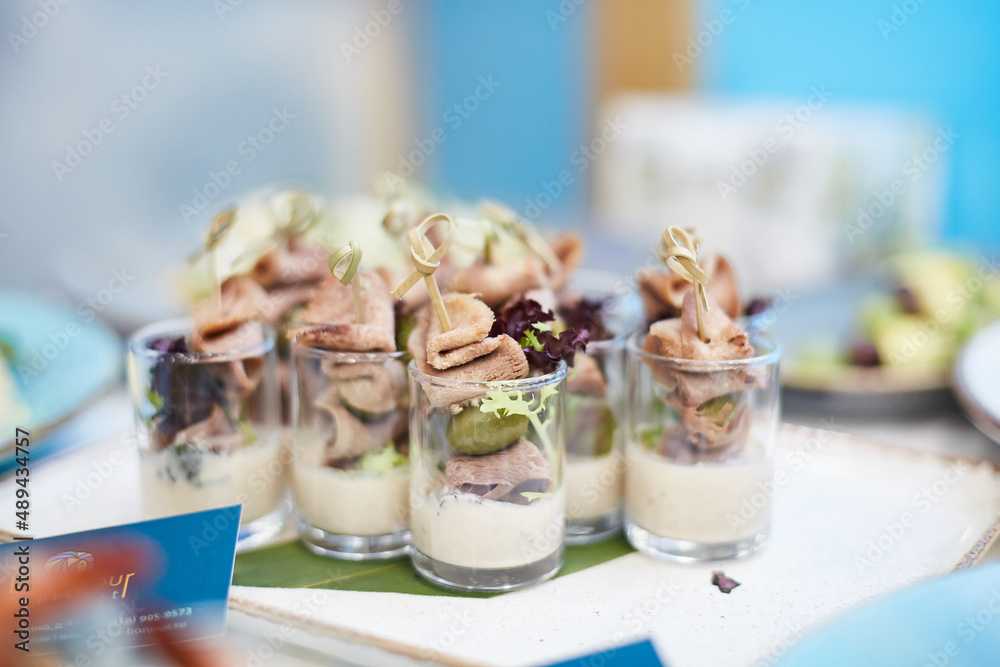 Delicious snacks with olives and meat in glass cups on the banquet ...