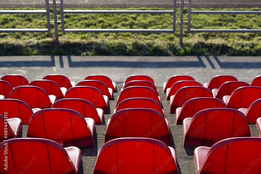 red benches of soccer - athletic stadium, sun set, place for spectators ...