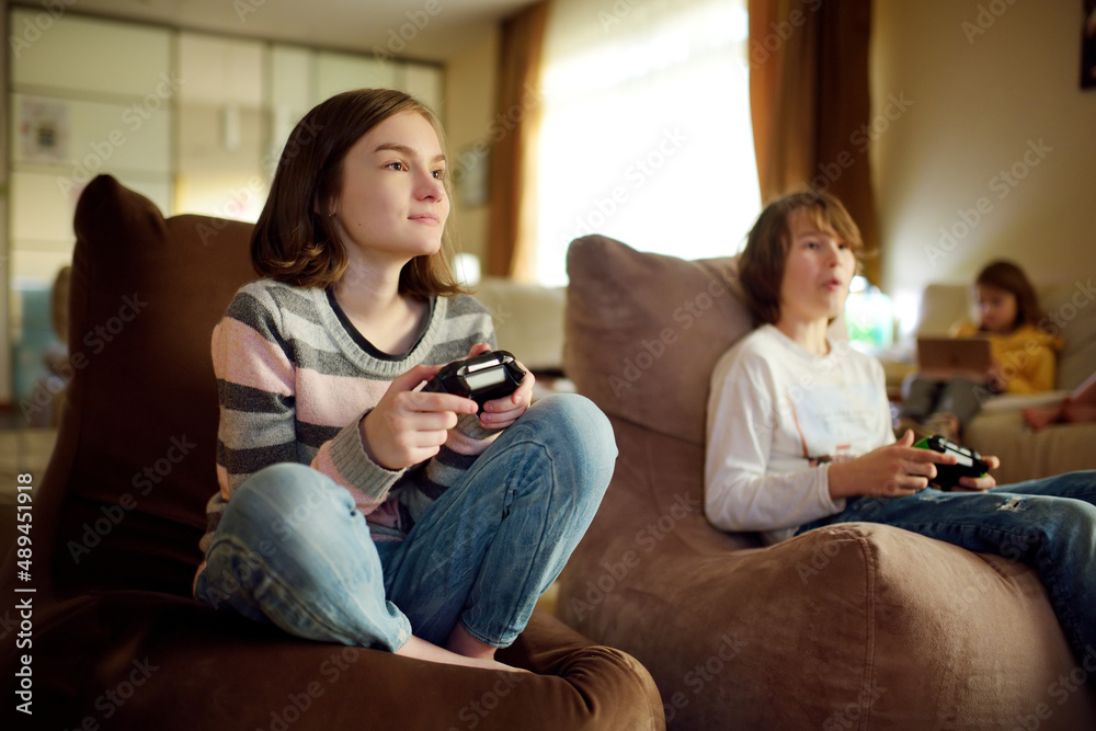 A group of preteen kids playing video games at home. Children sitting ...