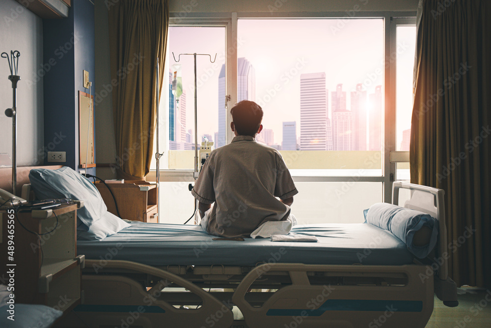 patient sat on the bed and looked out the window in the hospital alone ...
