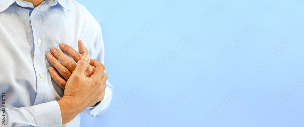 Hand squeezing the left chest pain on blue background concept of heart ...