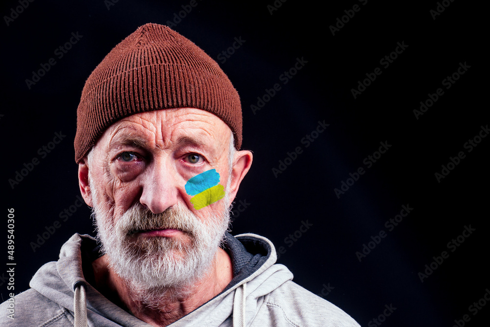 poor caucasian old men with Ukraine flag painted on cheek in studio ...