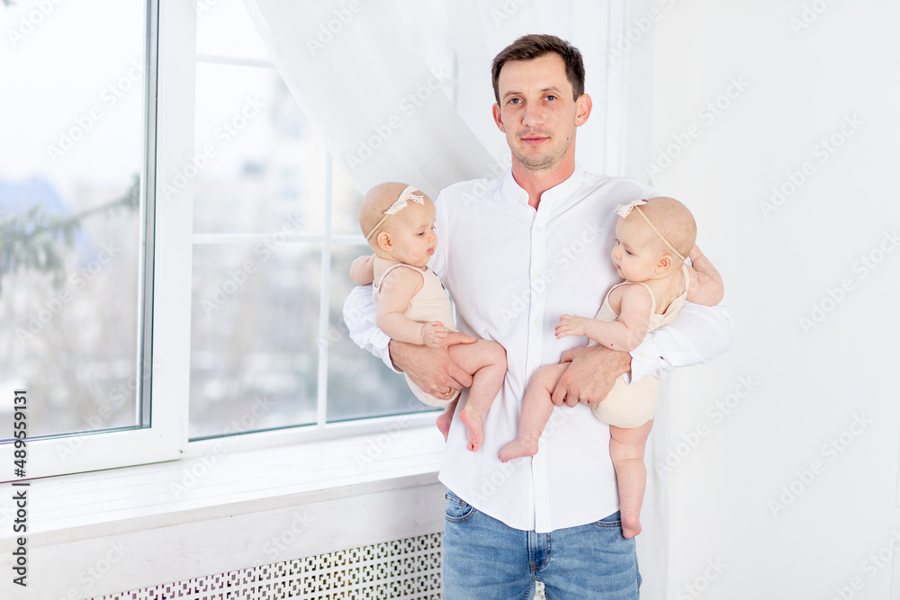 happy father with twins, daddy holds two newborn baby twin girls in a ...