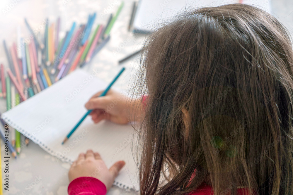 little girl coloring with crayons at the table,close-up of kindergarten ...