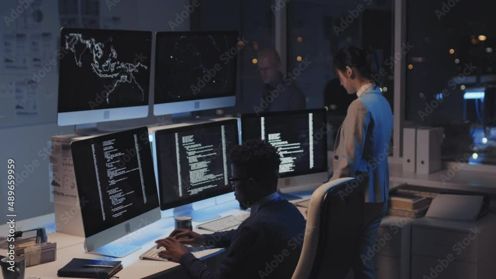 Side view of young Black man sitting at desk in corporate office ...