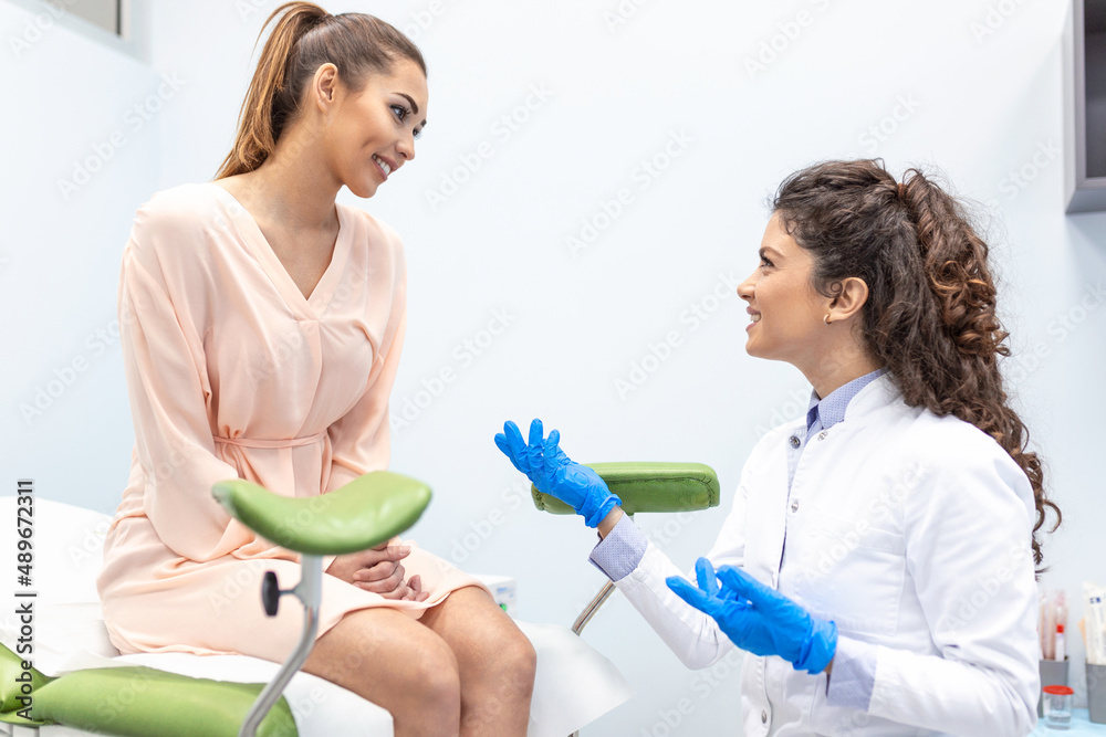 Gynecologist talking with a young female patient during a medical ...