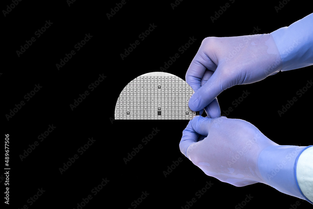 A hands in a rubber glove hold broken multilayer semiconductor silicon ...