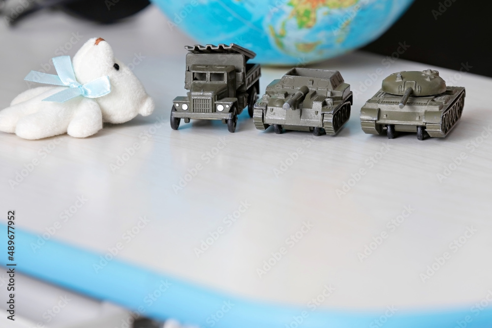 Metal toy tanks, an armored personnel carrier, and a white teddy bear ...