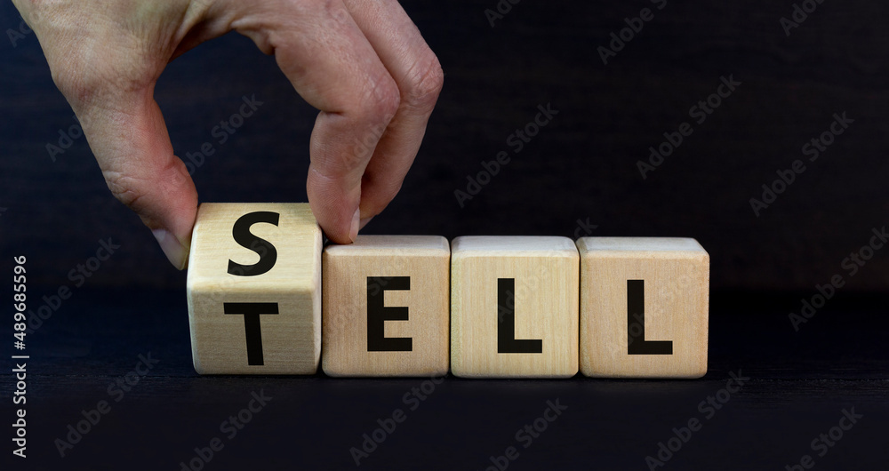 Sell or tell symbol. Businessman turns a wooden cube and changes the ...