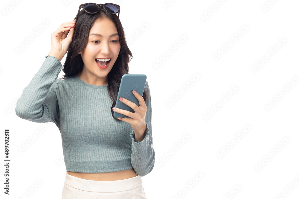 Happy and excited young woman using mobile phone standing over isolated ...