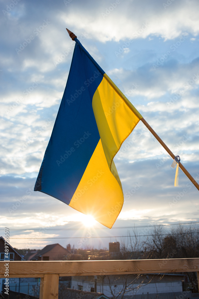 Ukrainian flag flutters in the wind and sunlight against the sunset sky ...