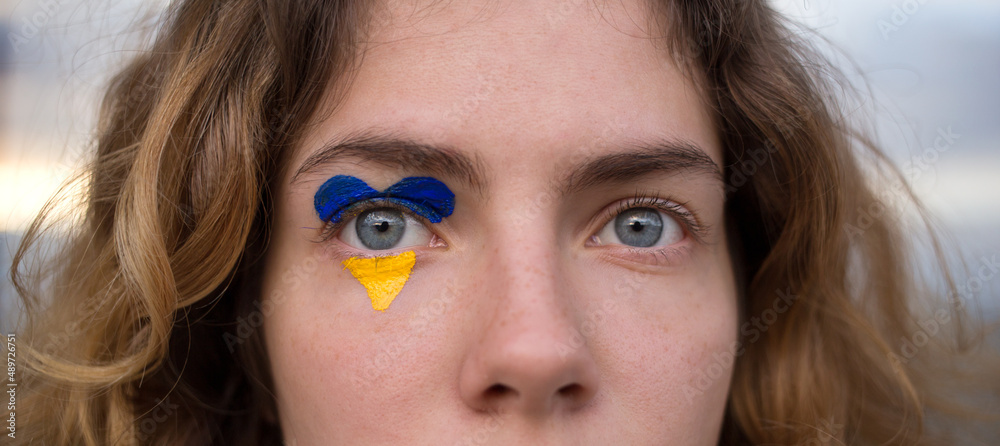 female eyes close-up with a drawn flag of Ukraine. National symbol of ...