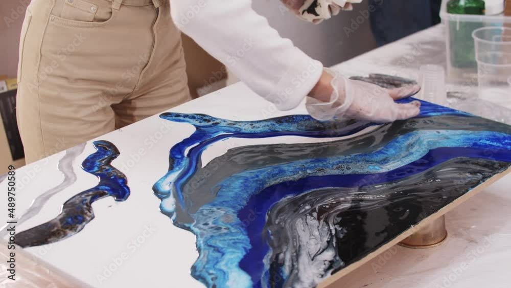 Applying dark blue epoxy resin on the painting with a finger vídeo de ...
