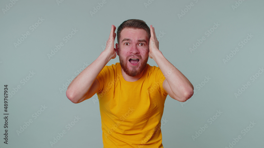 Bearded adult man scared fearful, covering ears with hands, closing ...