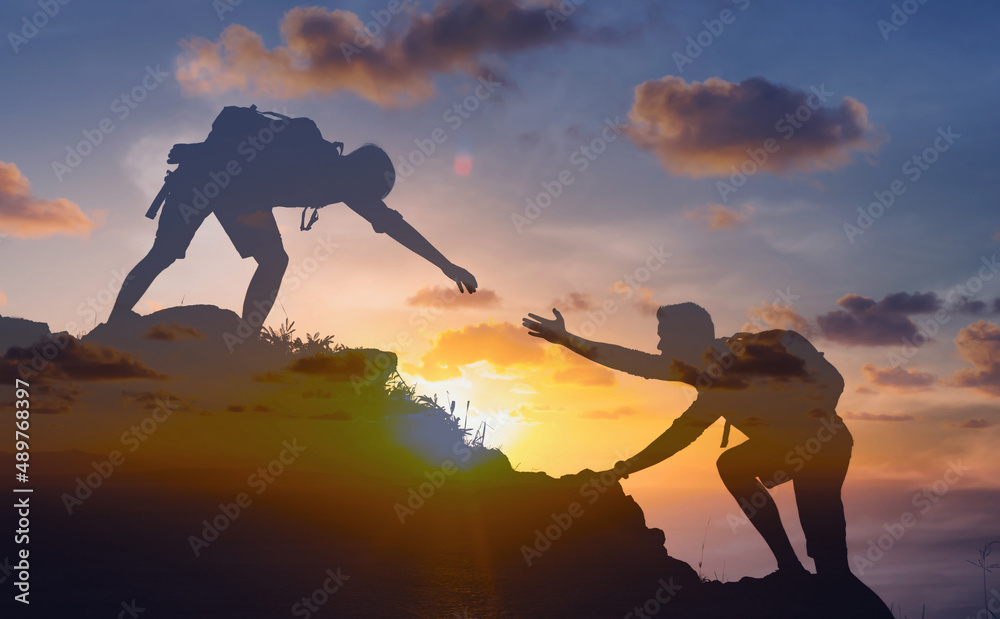 People working as a team helping each other climb a mountain ...