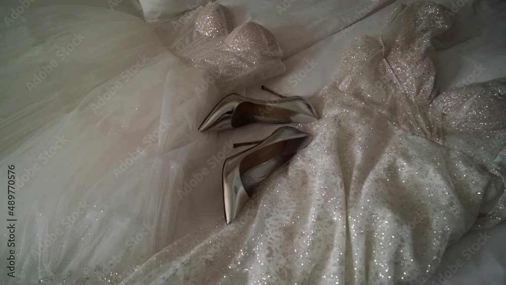 White bridal wedding gown laying on bed linen in bedroom. Luxury bride ...