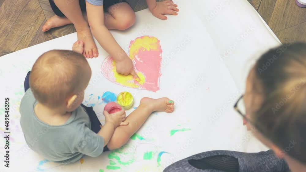 baby children drawing with finger paints pink heart white paper. mother ...