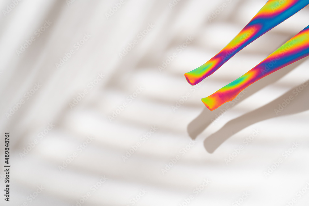 Neon colored doll legs on white background with palm tree shadow Stock ...