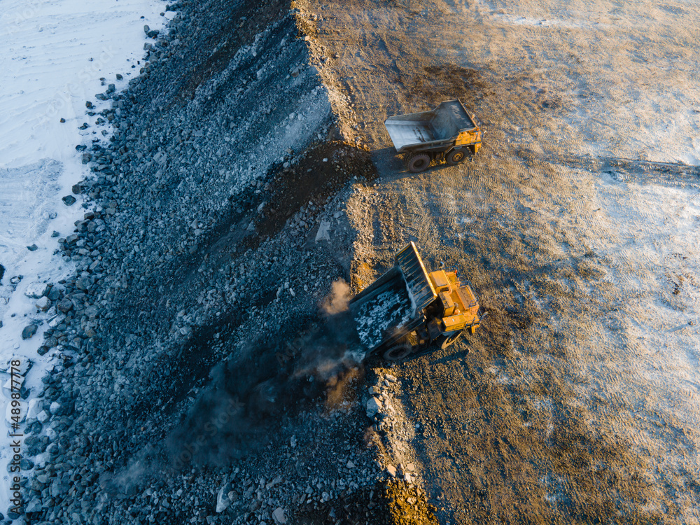 Loading rock mass into a truck. Excavator at work. Mining. flying drone ...