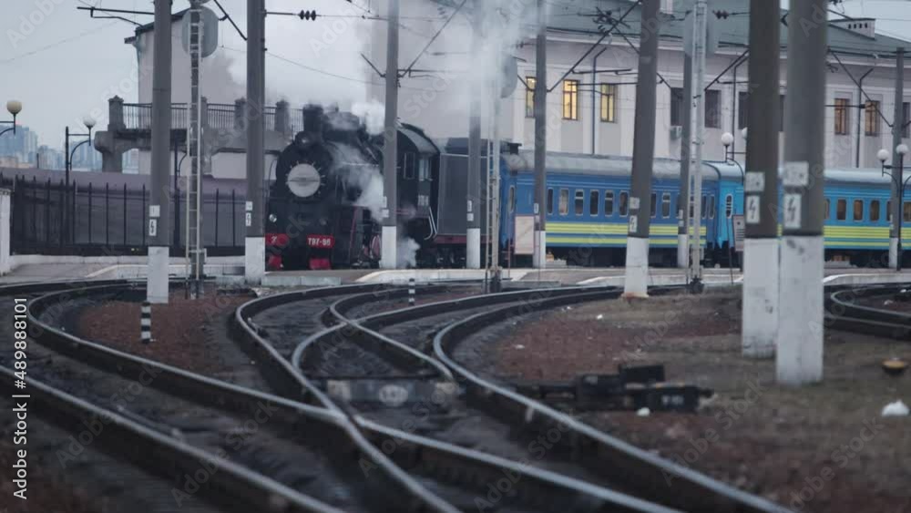 Steam locomotive train approaching station passing through a goods yard ...