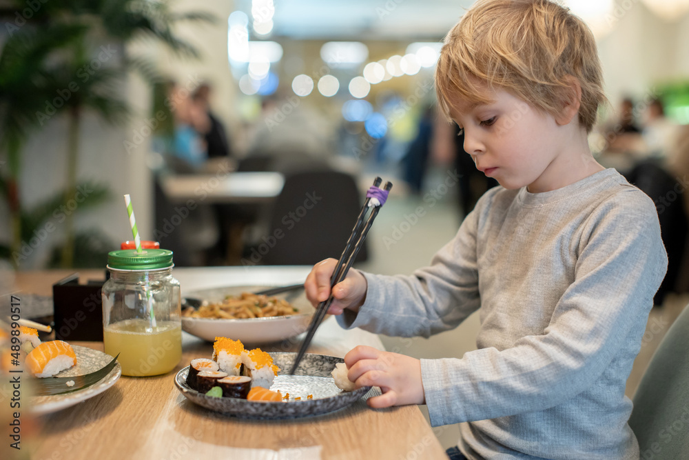 Child, eating japanese sushi and noodles with chopsticks in a ...