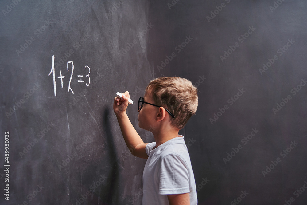 Primary education. Side view student solves math example on a ...