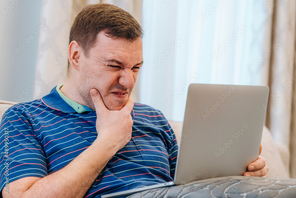 Annoyed millennial man with disgust confused looking at laptop screen ...